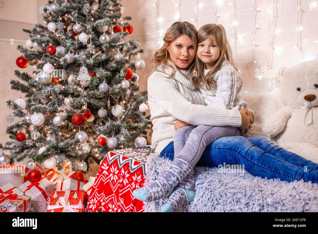 Daughter cutely sits on her mother's lap against the background of a ...