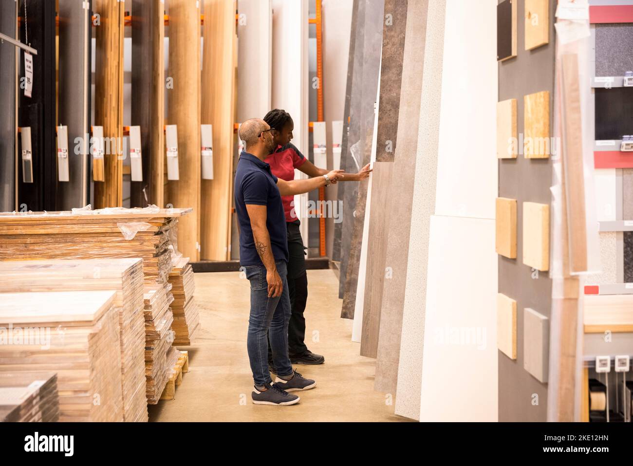 Side view of male customer with saleswoman choosing laminated boards at ...