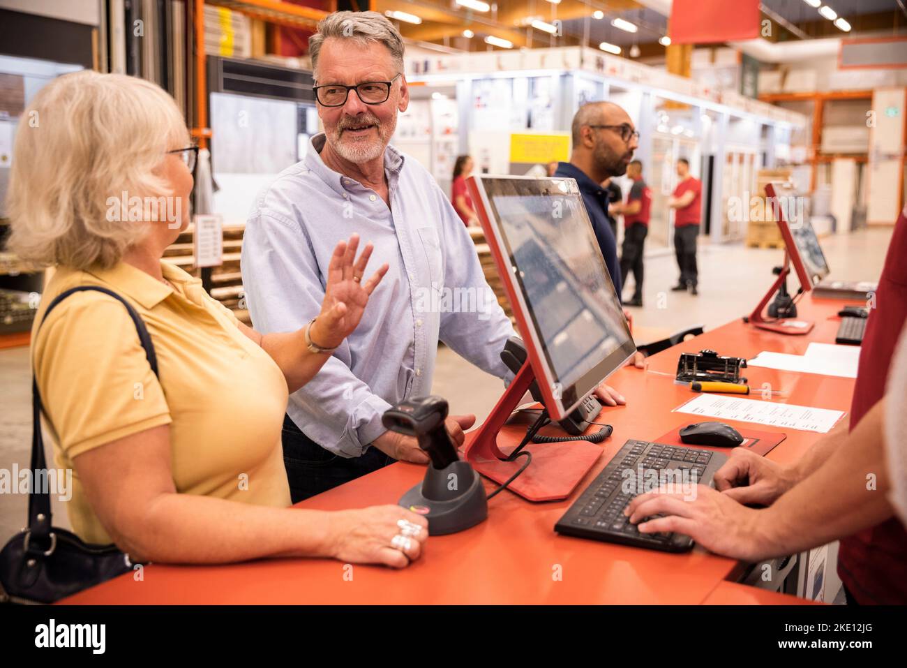 Senior male and female customers talking with each other while standing ...