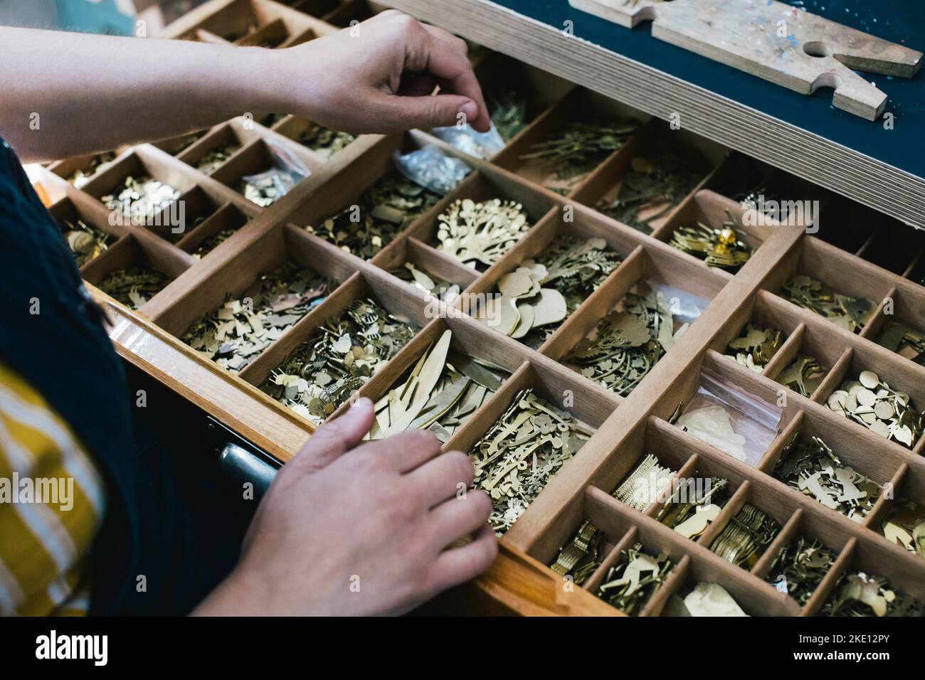 Female craftsperson opening drawer with jewelry making materials Stock ...