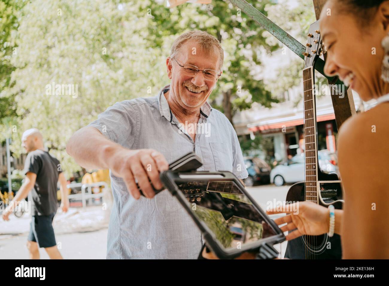 Happy senior male customer paying through contactless payment while ...