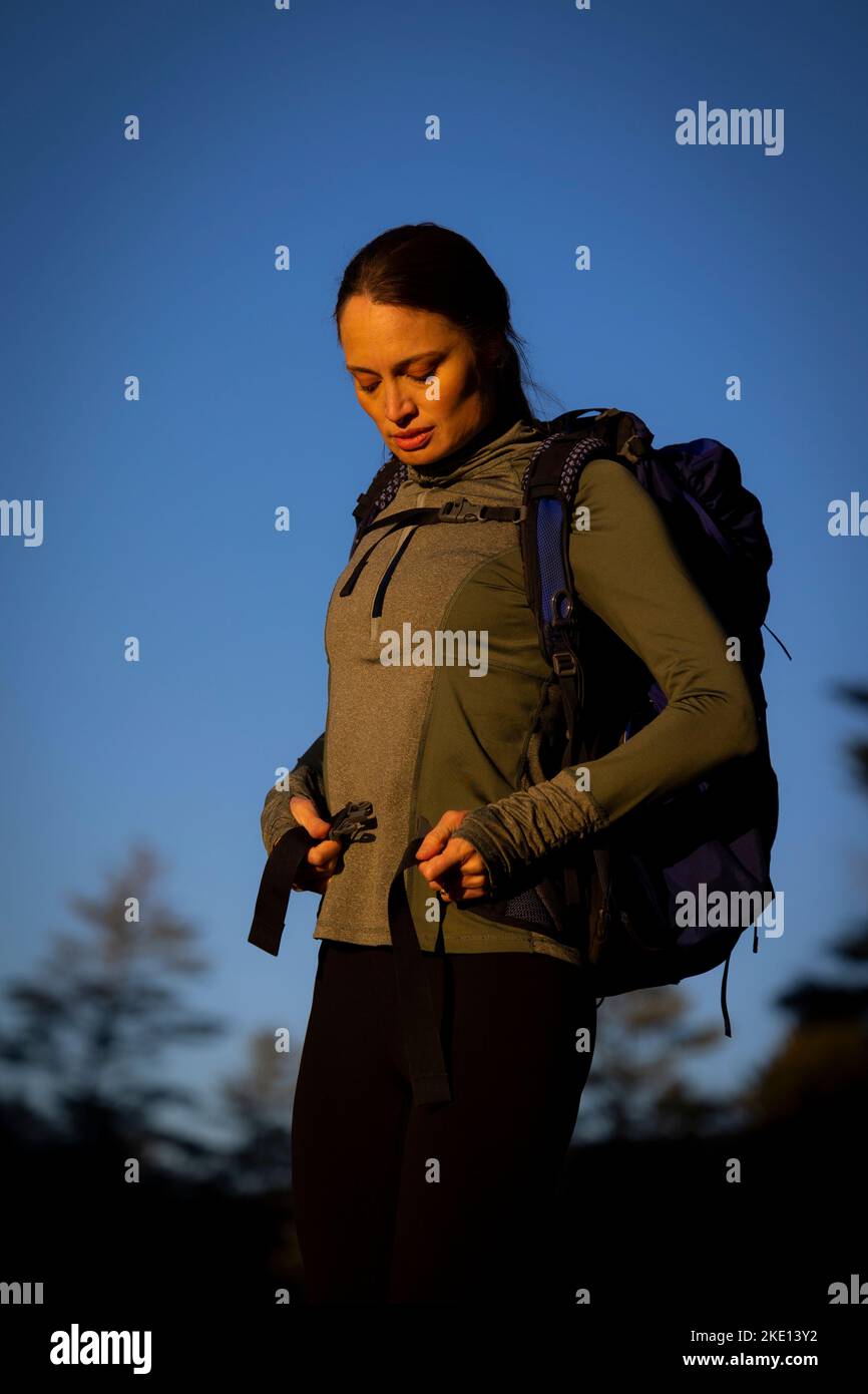 A woman putting on her backpack Stock Photo - Alamy