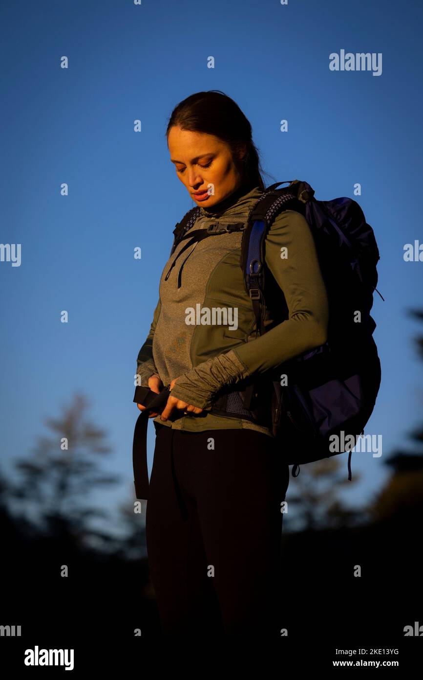 A woman putting on her backpack with blue sky in the background Stock ...