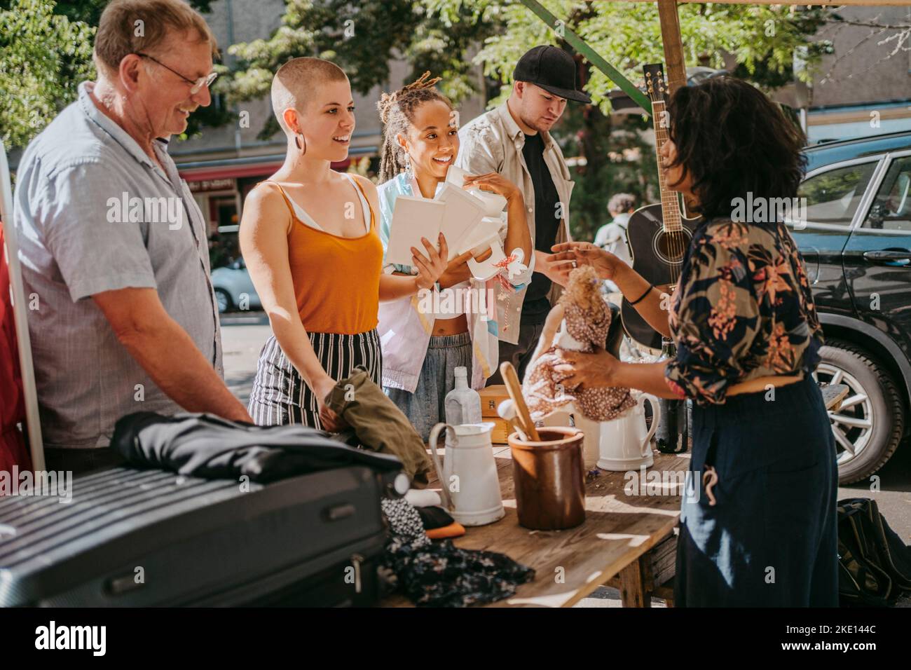 Side view of female owner interacting with customers doing shopping at ...