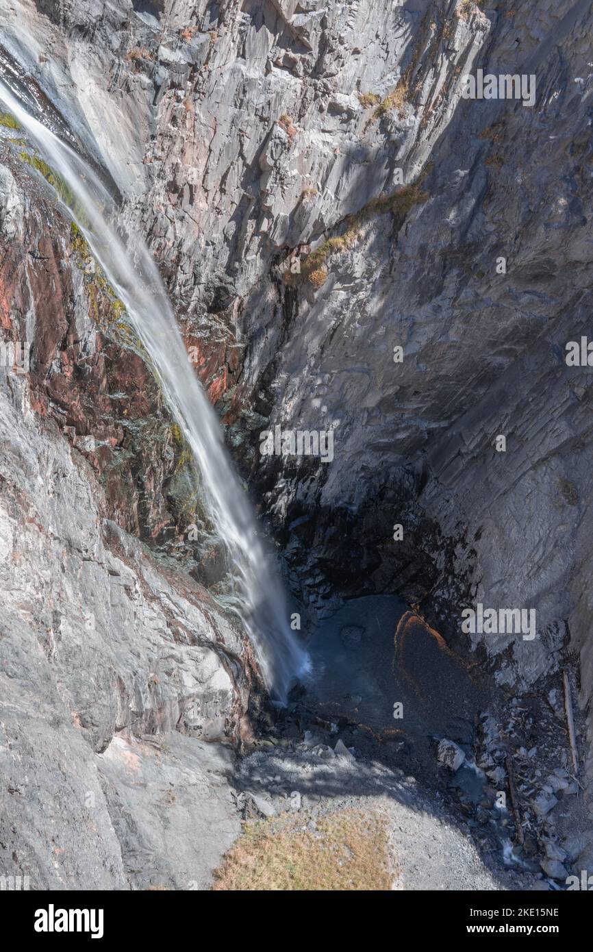 A vertical shot of the long narrow Bear Creek Falls surrounded by rocky ...