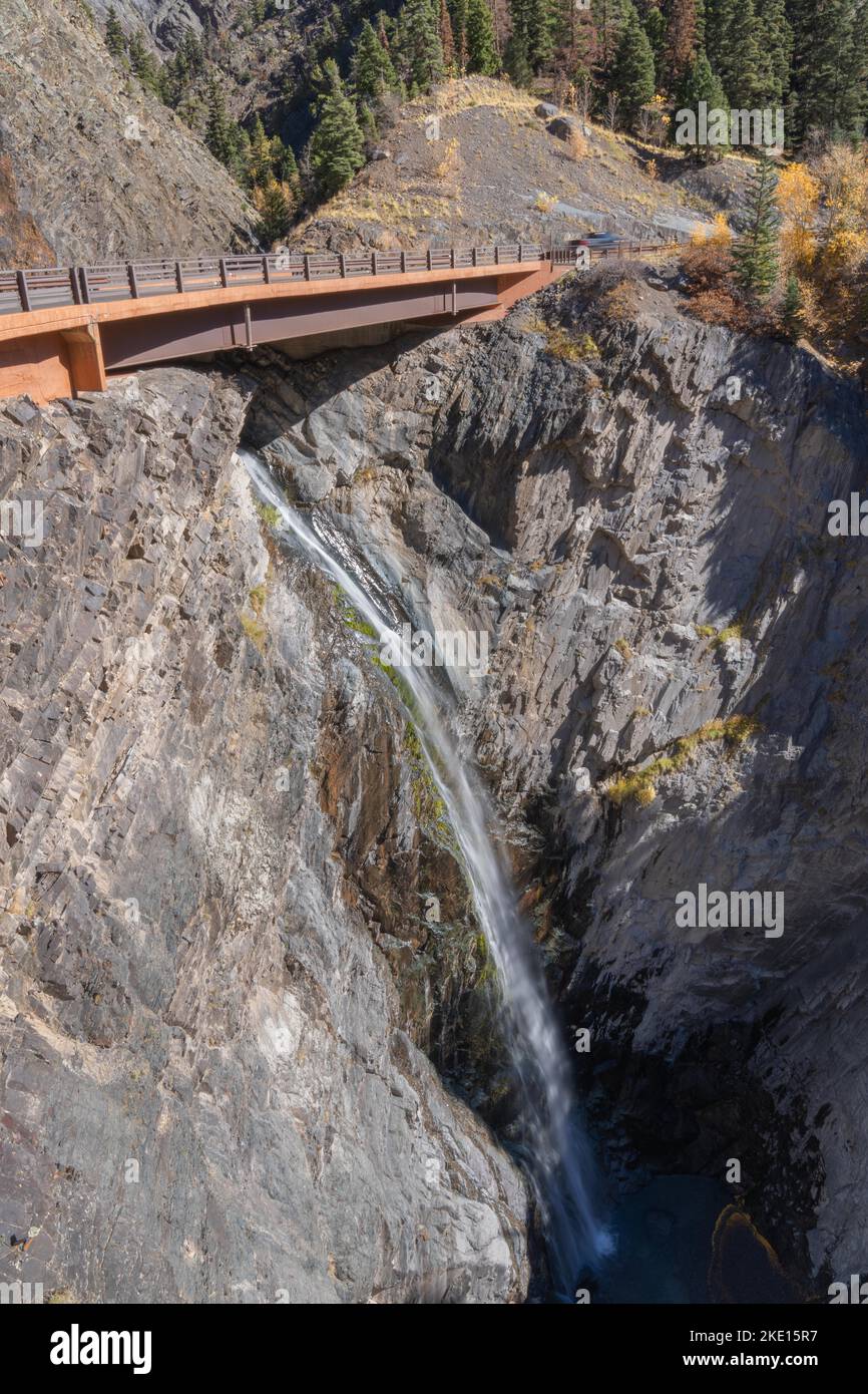 A vertical shot of a road over the narrow Bear Creek Falls surrounded ...