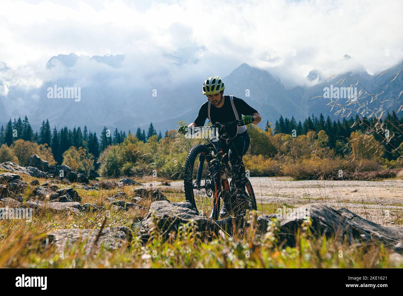A young professional male riding a mountain bike on a trail near ...