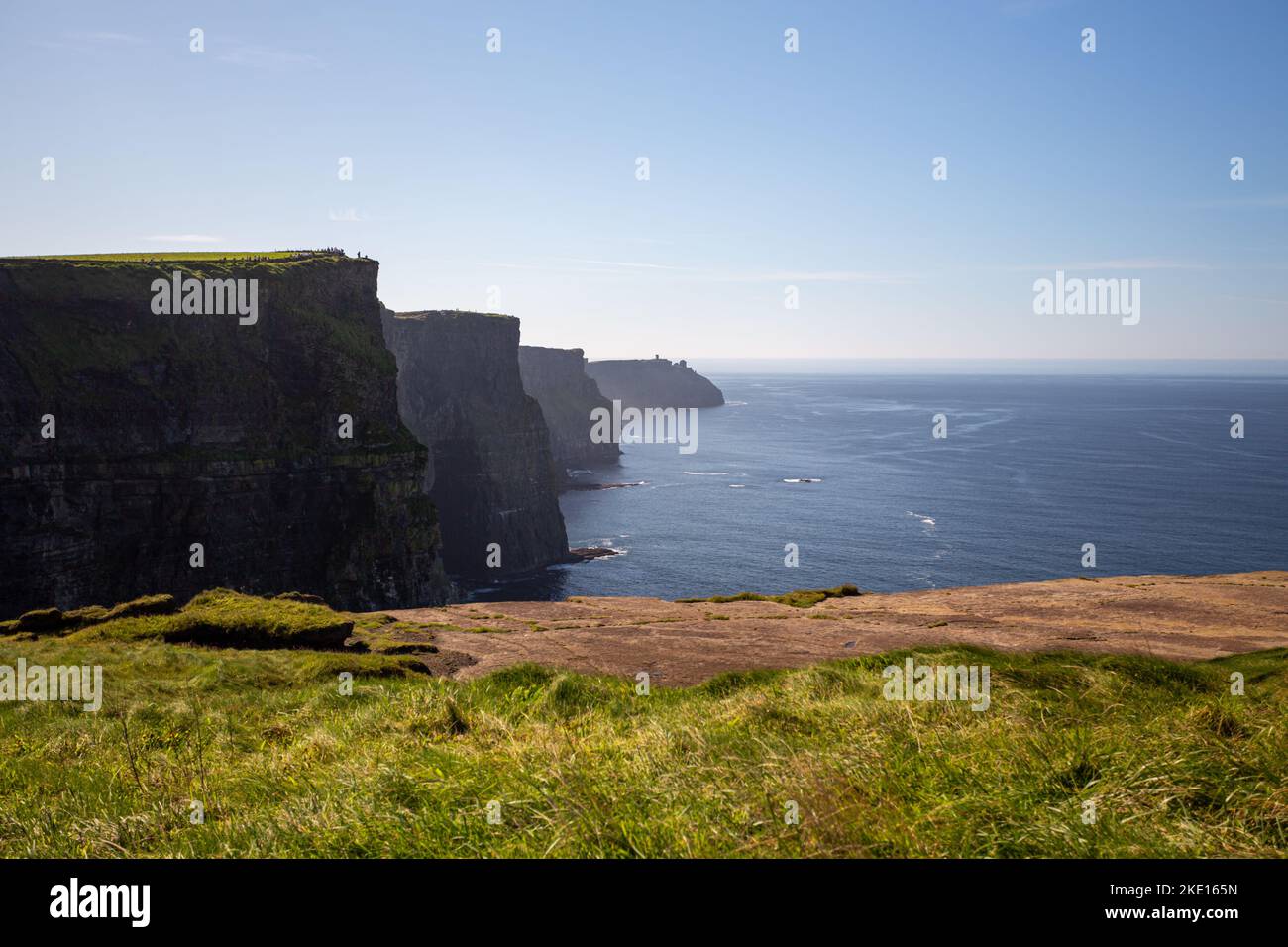 A scenic view of green Cliffs of Moher against the blue ocean on a ...