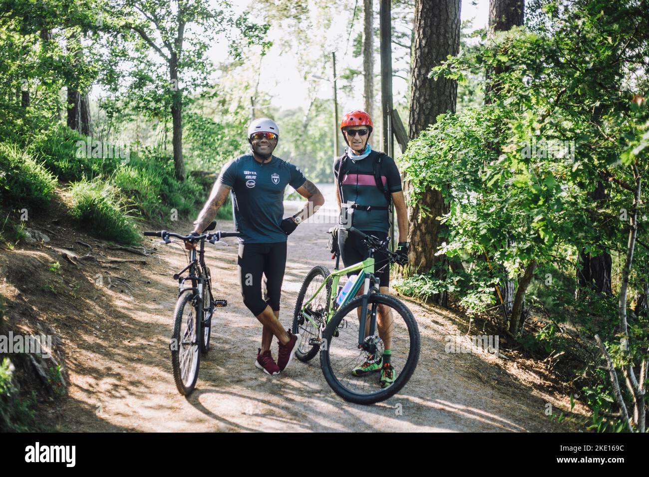 Male friends standing with cycles on footpath Stock Photo - Alamy