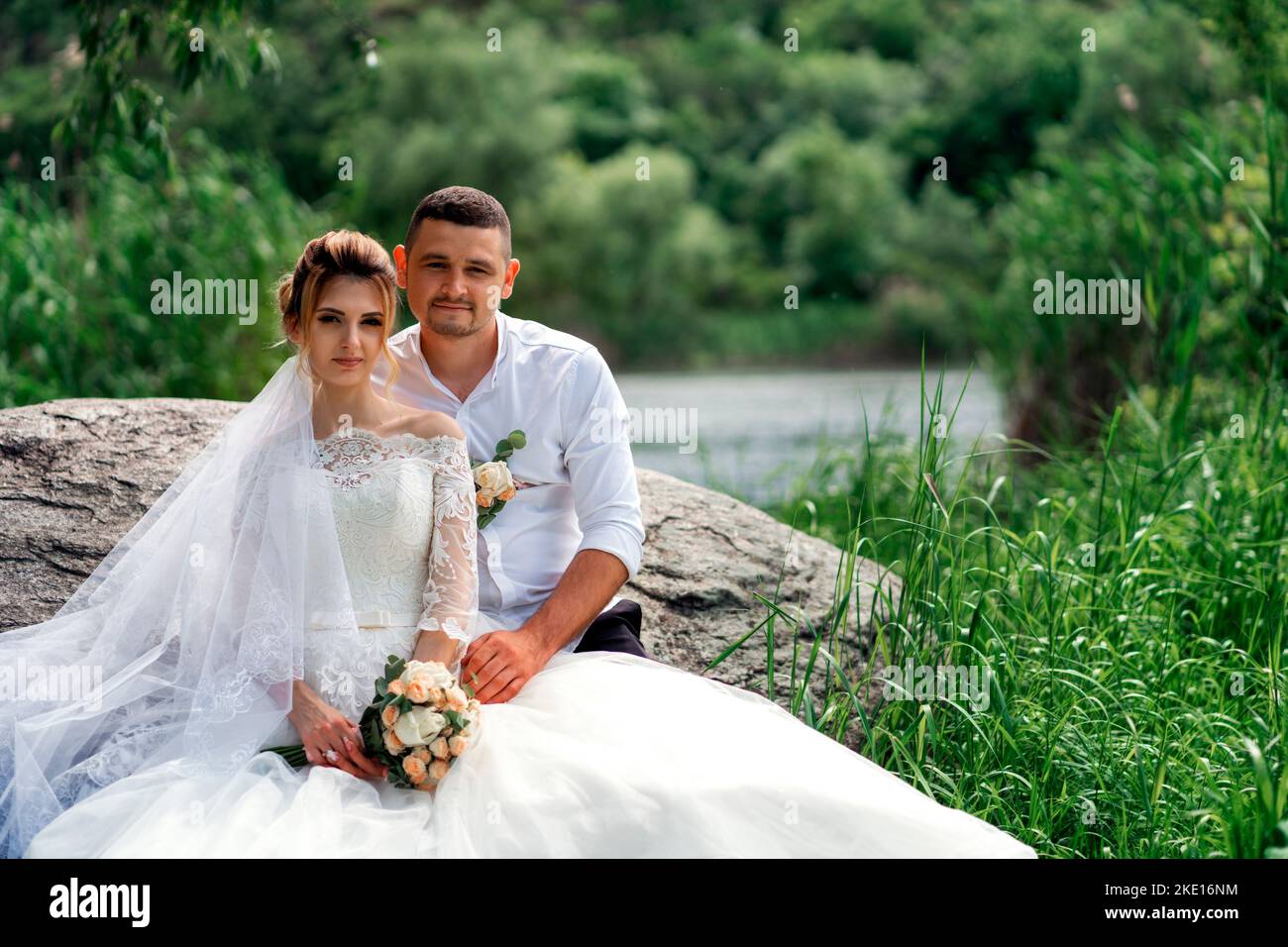 The bride and groom look into the distance on the river bank Stock ...