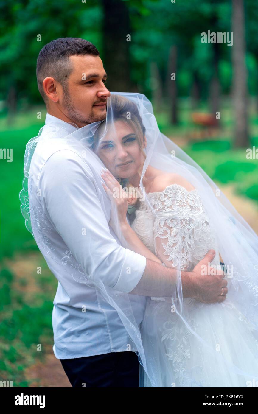 Bride in veil hugging groom Stock Photo - Alamy