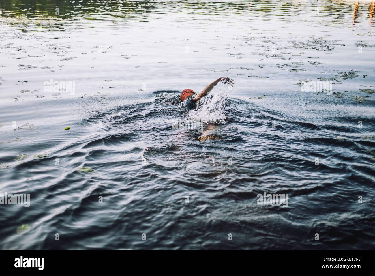 Mature man splashing water while practicing freestyle swimming in lake ...
