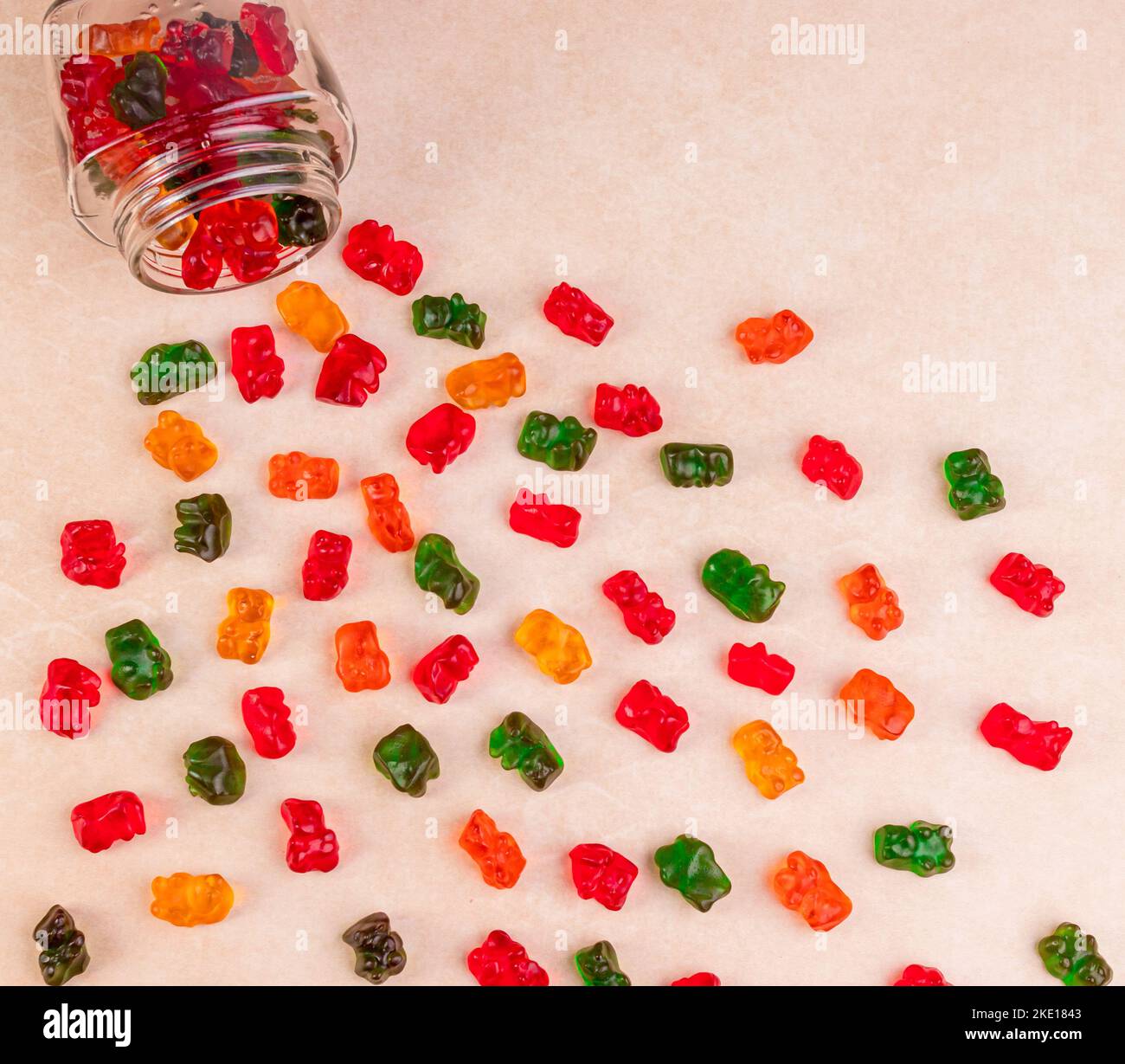 A top closeup of flavored and sugared soft gummies on the beige table ...