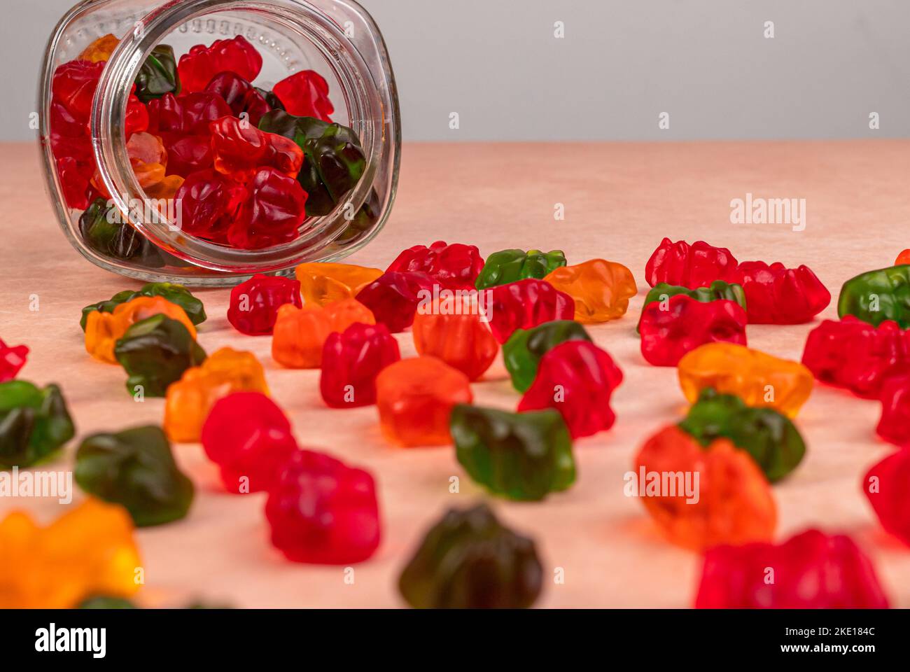 A side closeup of flavored and sugared soft gummies on the beige table ...