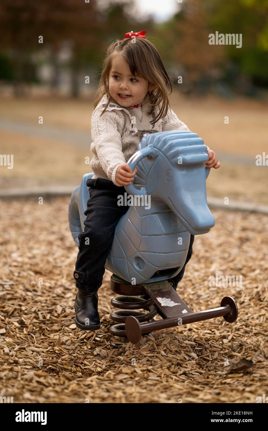 Adorable 3 years old little girl riding a playground creature and ...