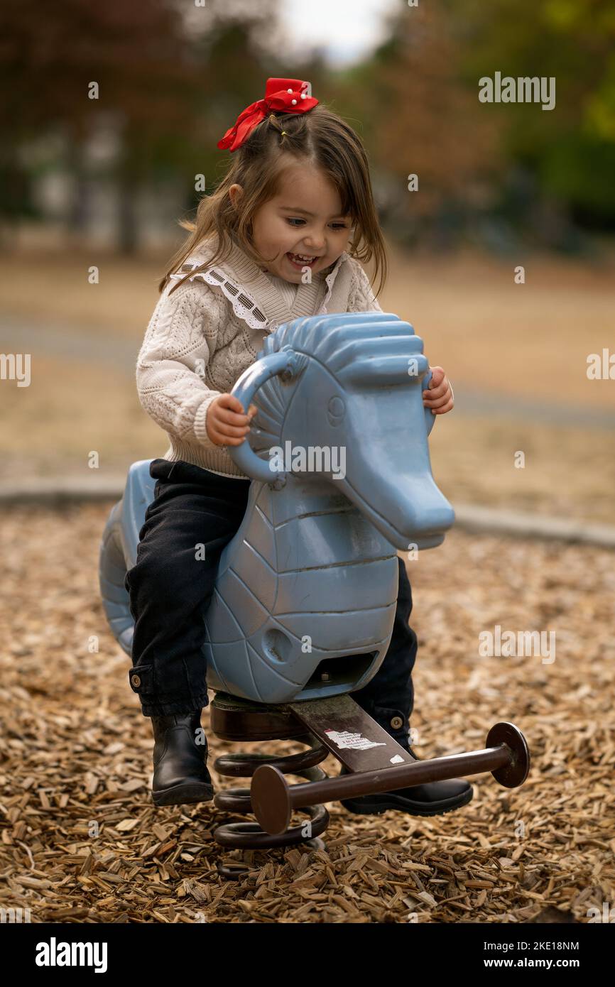 Adorable 3 years old little girl riding a playground creature and ...