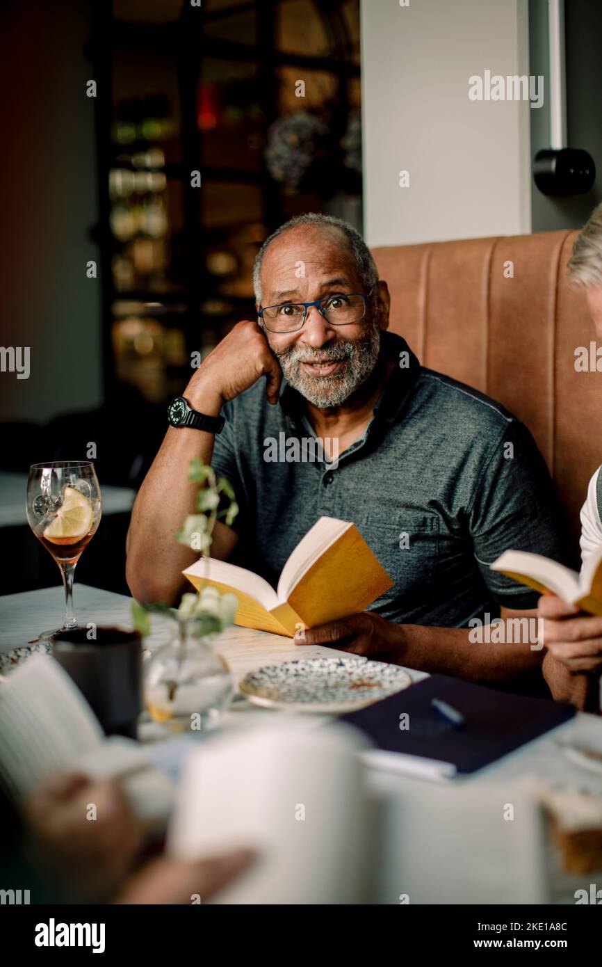 Senior man wearing eyeglasses sitting with book in cafe Stock Photo - Alamy