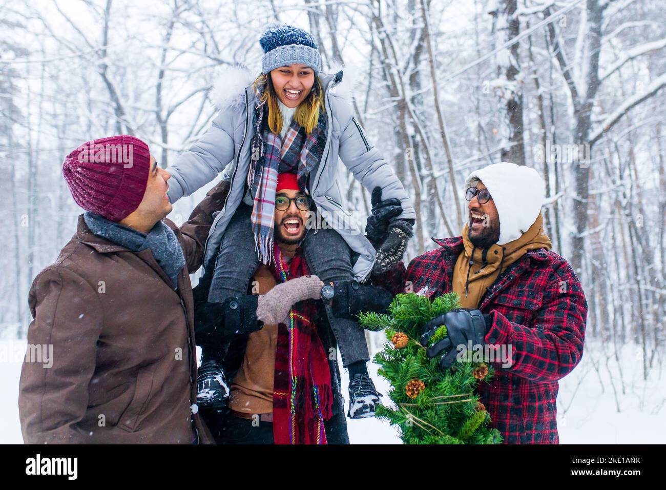 Outdoor lifestyle portrait of four best friends carrying the tree to ...