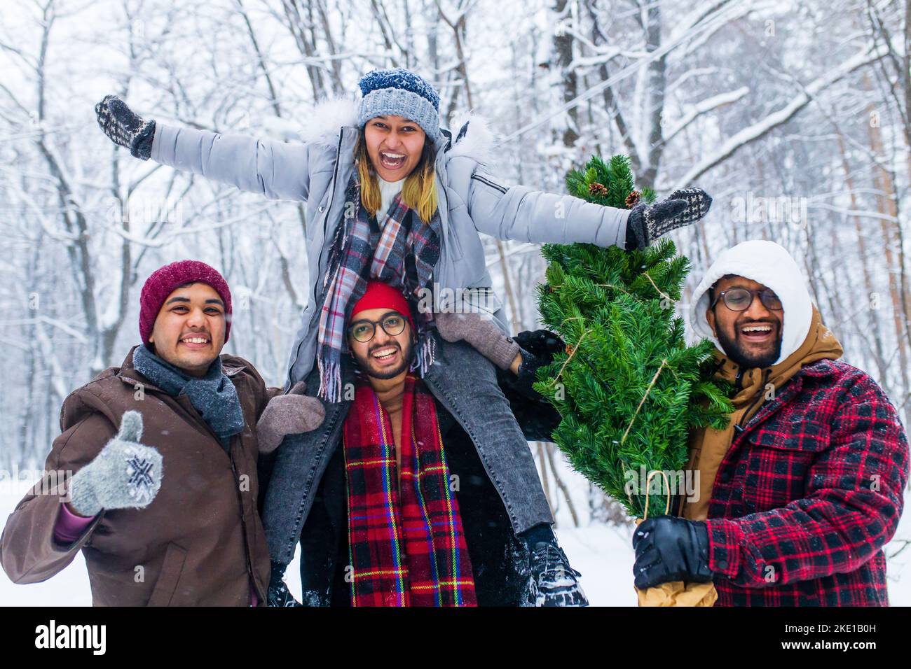 Outdoor lifestyle portrait of four best friends carrying the tree to ...