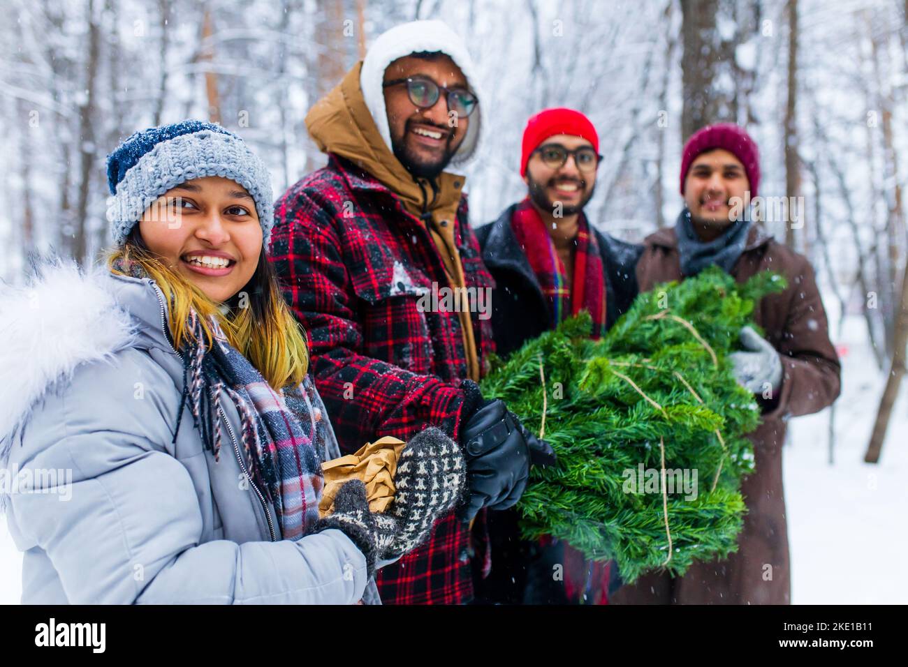Outdoor lifestyle portrait of four best friends carrying the tree to ...