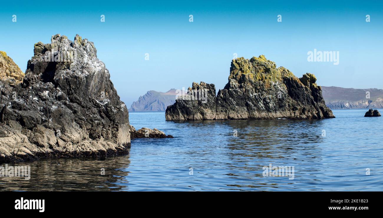 Rocks with Blasket Island in the background and a clear blue sky near ...
