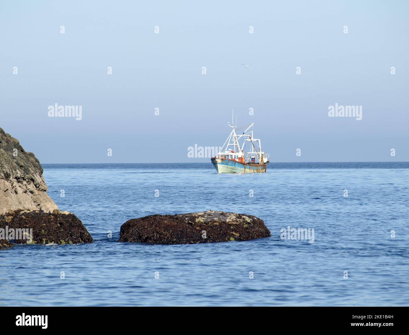 Fishing cutter in front of clear blue sky with some rocks near Slea ...
