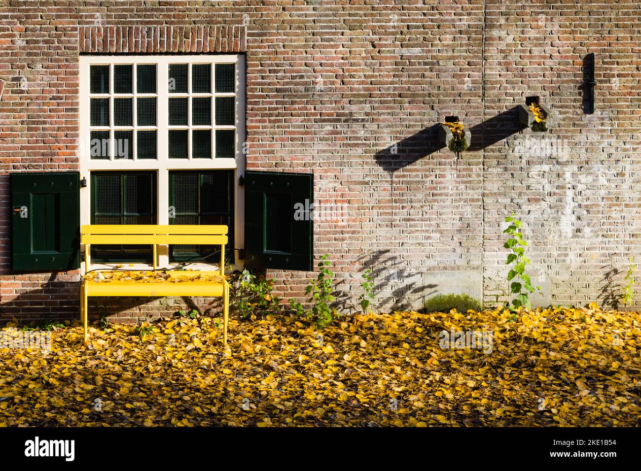 Yellow bench and autumn leaves in the historic city centre of Utrecht ...