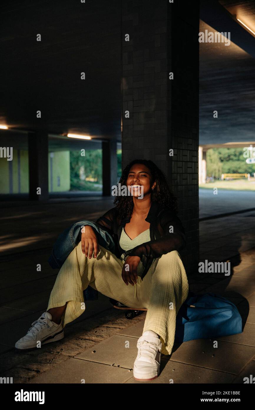 Full length of happy teenage girl sitting against column Stock Photo ...