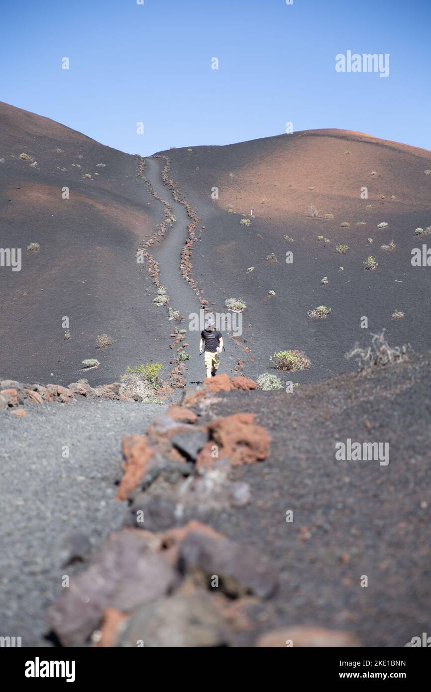 A vertical shot of Volcano Chinyero and a man walking down to the ...