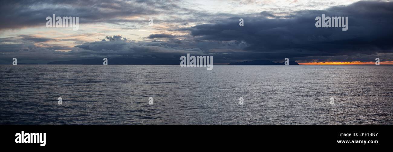 A panoramic shot of the sea sunset with a half-cloudy sky and an orange ...