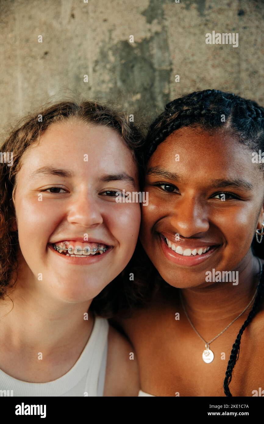 Happy teenage girl wearing braces by female friend against wall Stock ...