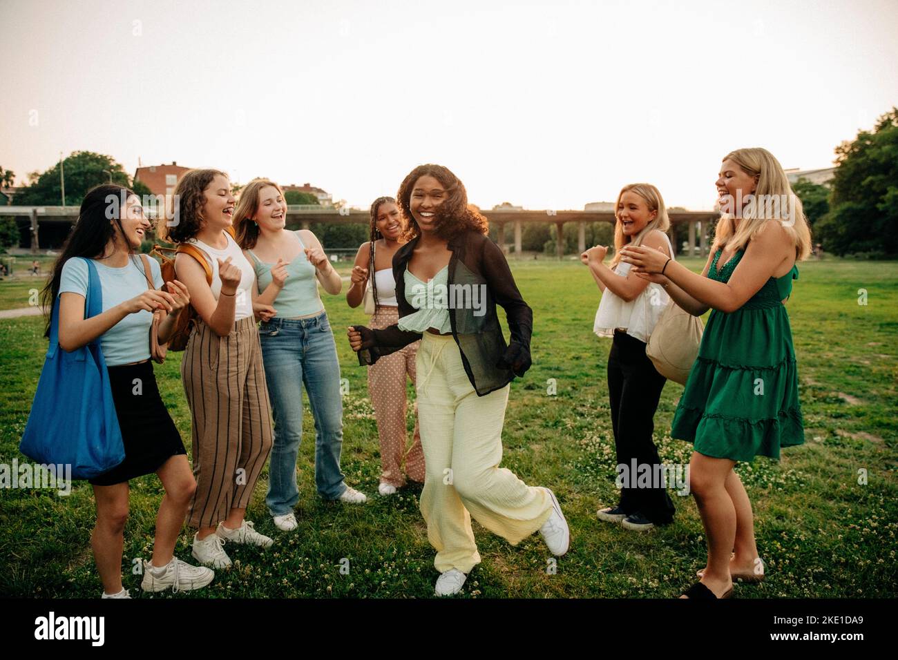 Teenage girls cheering friend dancing in park at sunset Stock Photo - Alamy