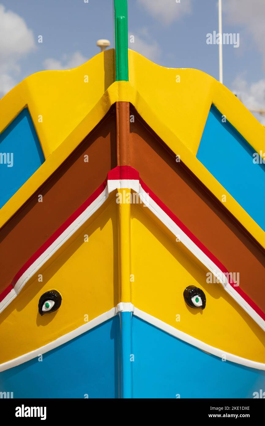 A vertical shot of a luzzu boat over a background of a cloudy sky ...