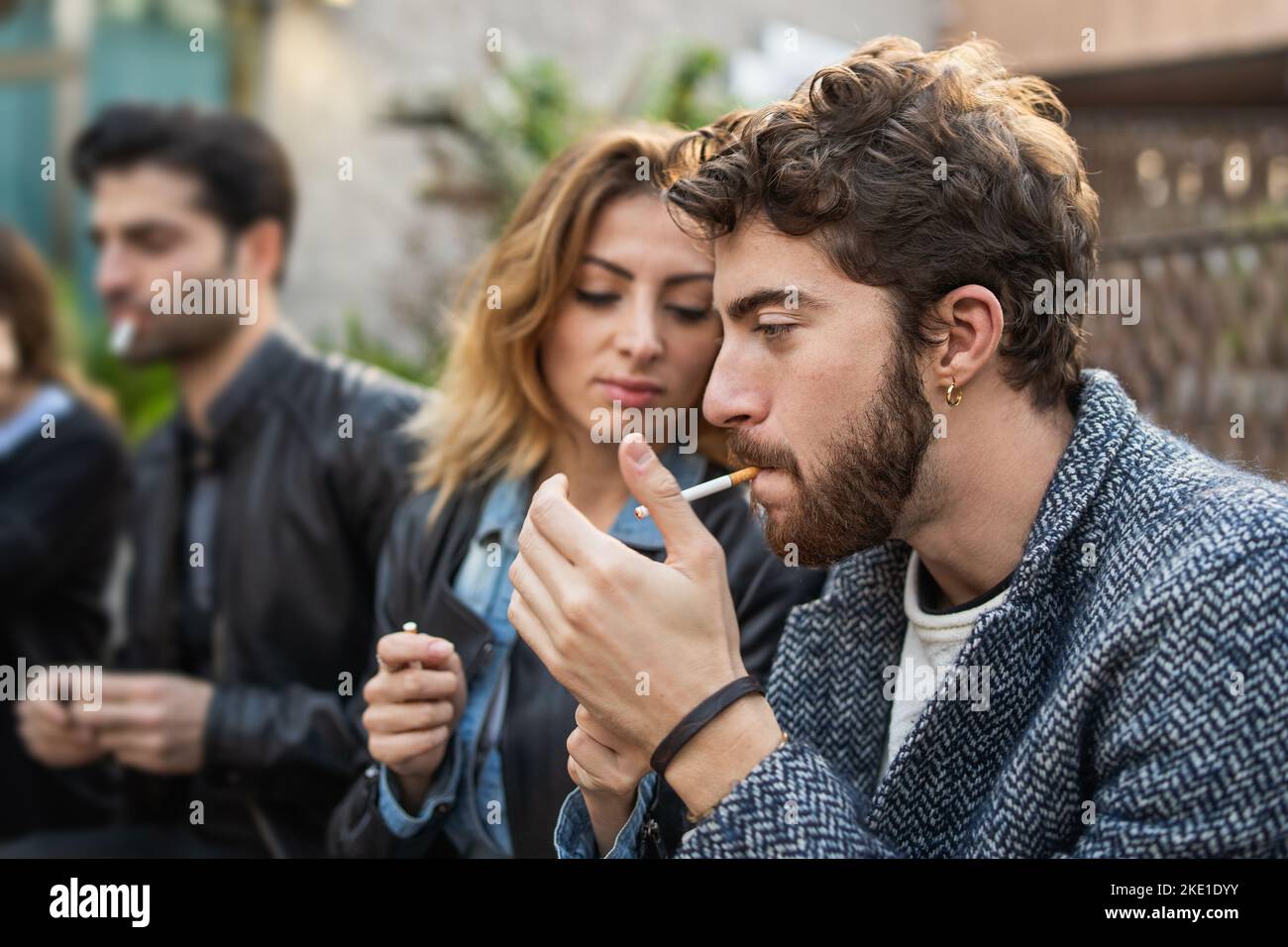 Group of friends lighting cigarettes and smoking together sitting on a ...