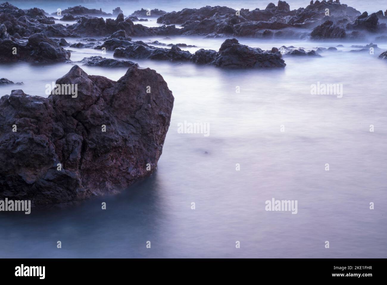 Dark stones in ocean water, ideal for background Stock Photo - Alamy