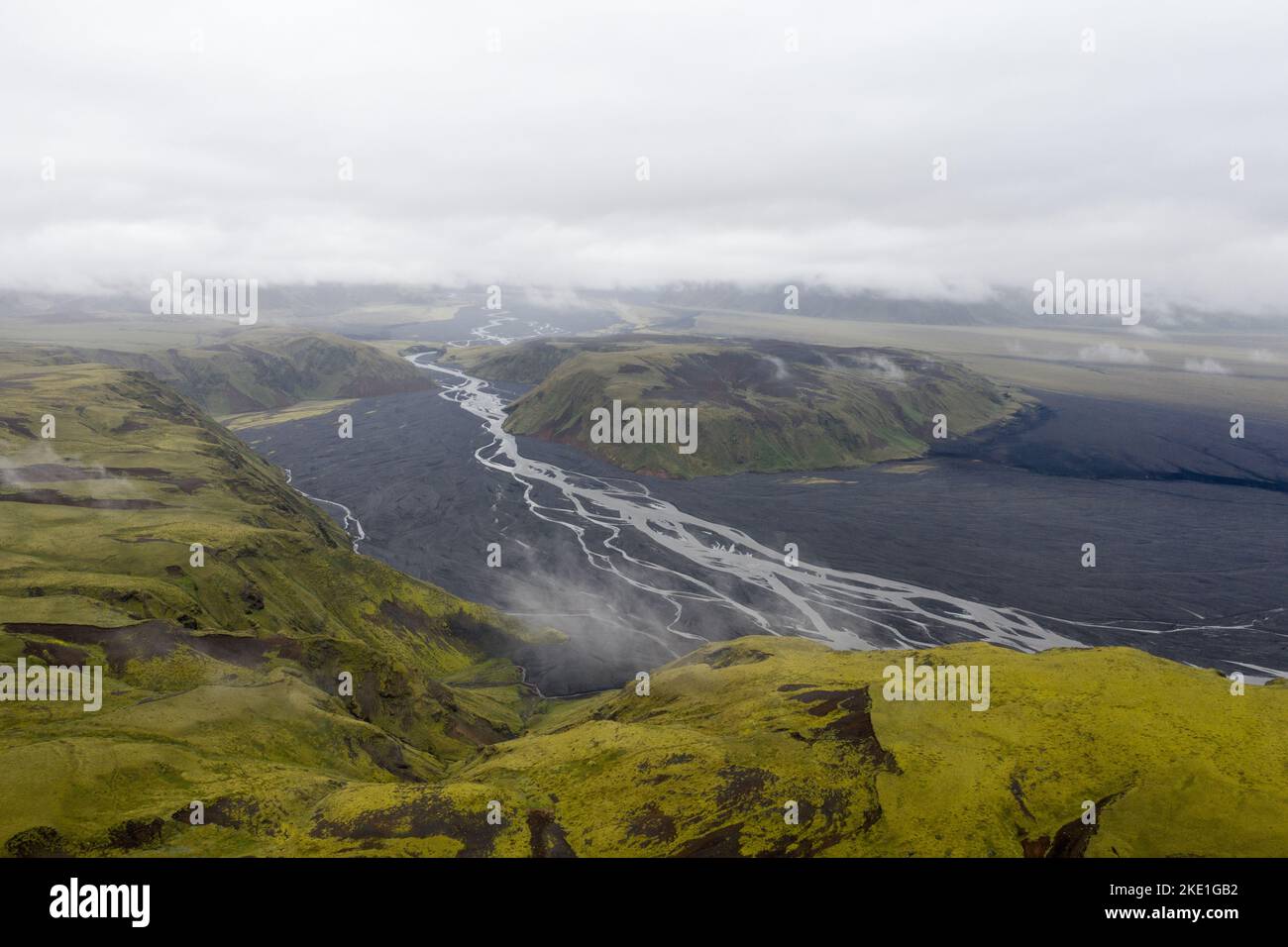 An aerial shot of a rover flowing trough the green-covered mounts in ...