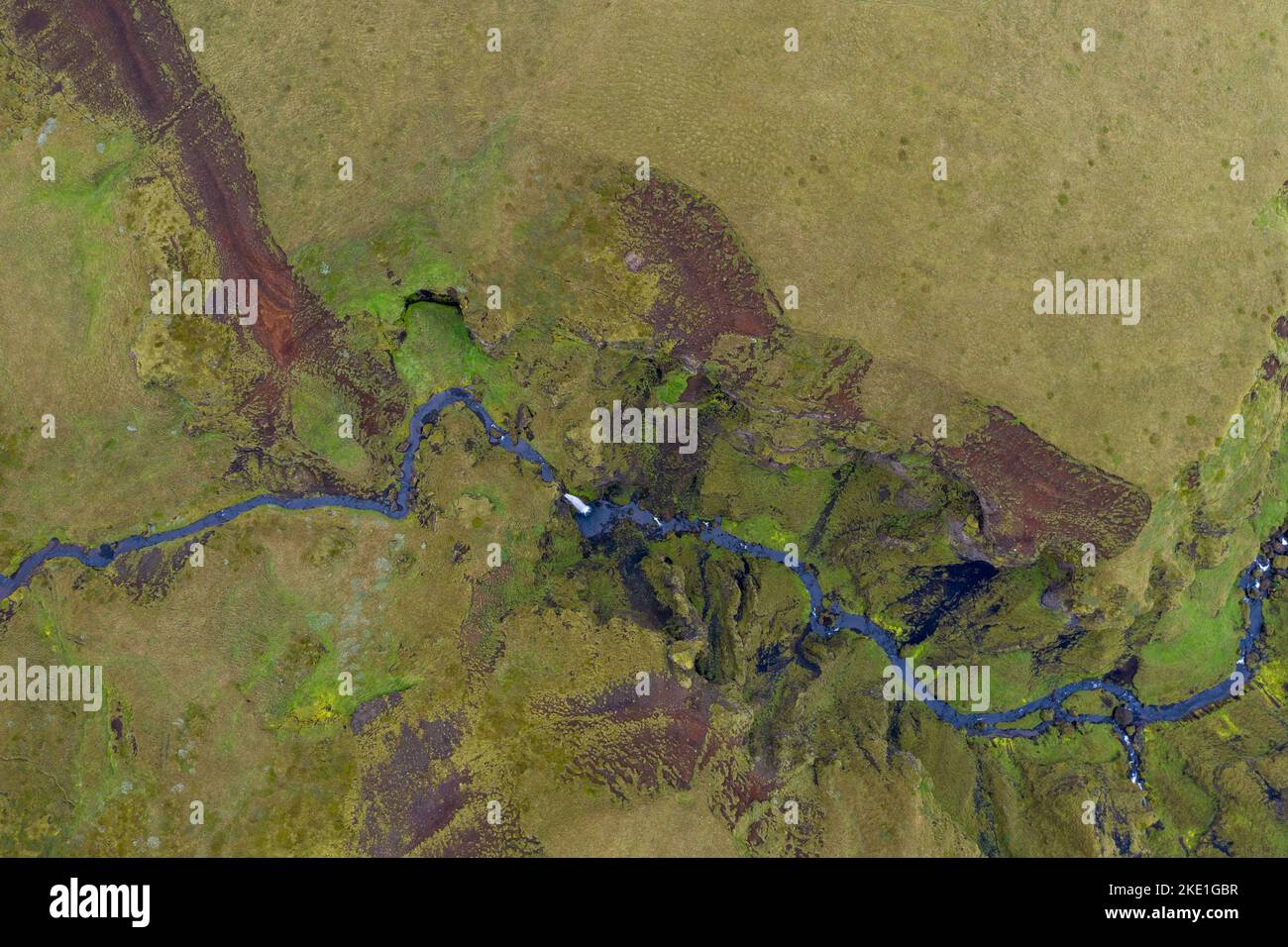 An aerial shot of a rover flowing trough the green-covered mounts in ...