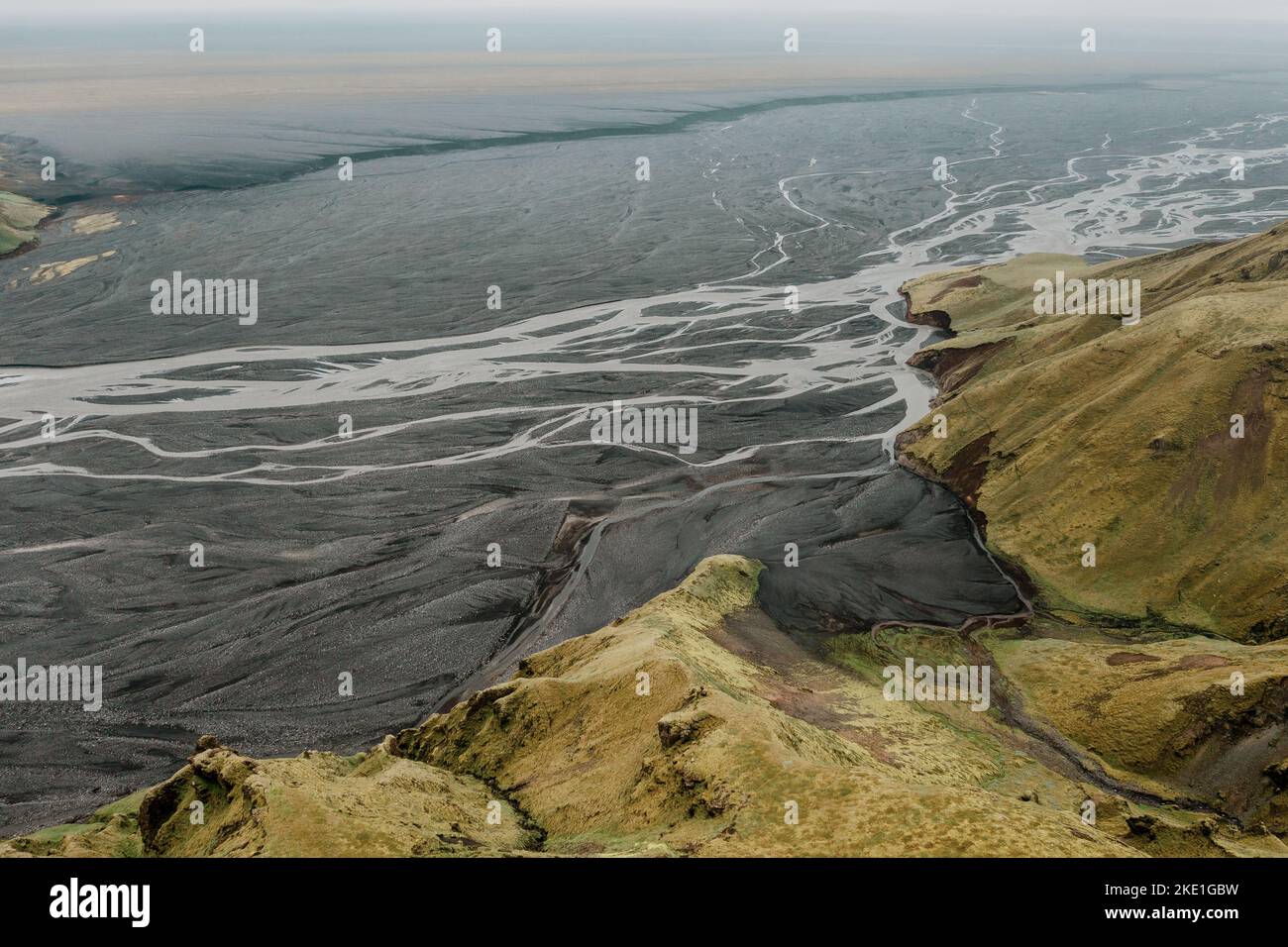 An aerial shot of a river flowing trough the green-covered mounts in ...