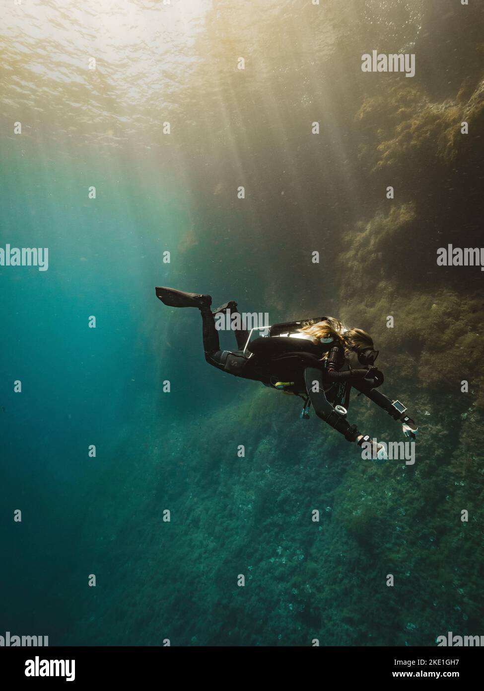 A vertical of rebreather technical diver on the sunlit ocean diving ...