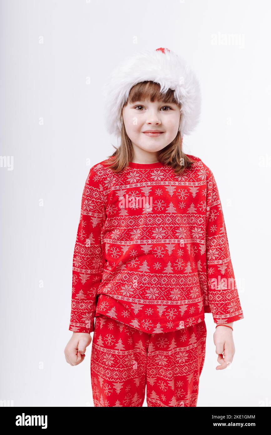 Pretty child girl in winter red pyjamas with holiday print, Santa hat ...