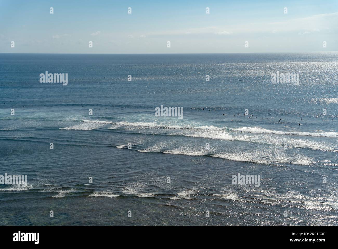 A high-angle of a beach in Bali with water waves making foam, sunlit ...
