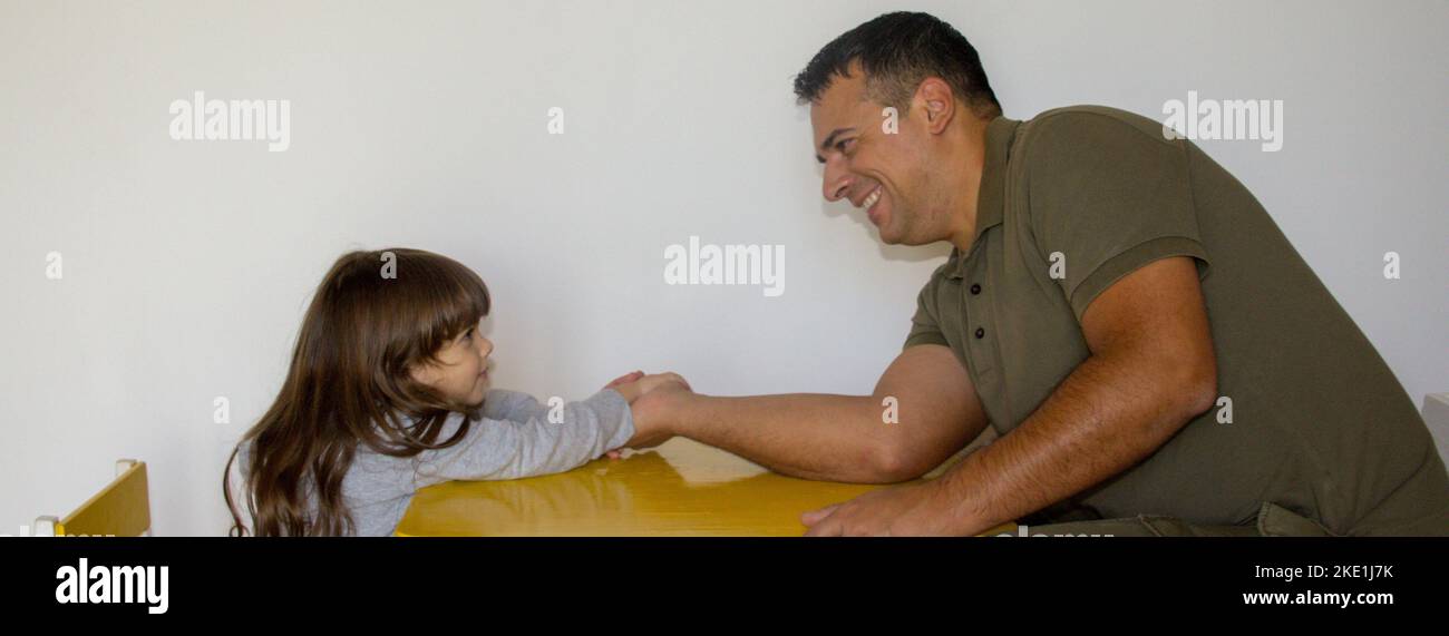 Image of a dad playing arm wrestling with his daughter. Parent defeated ...