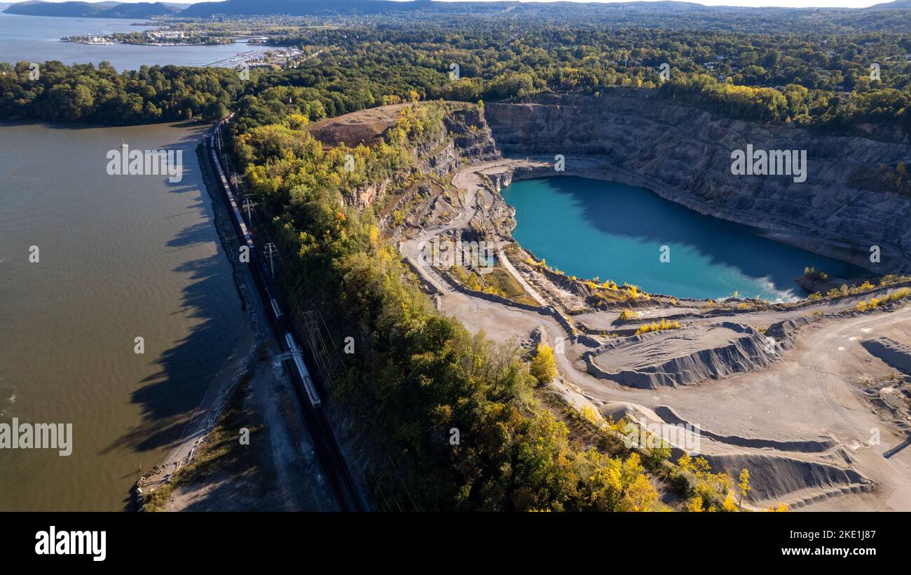 An aerial view over a rock quarry with turquoise colored water in ...