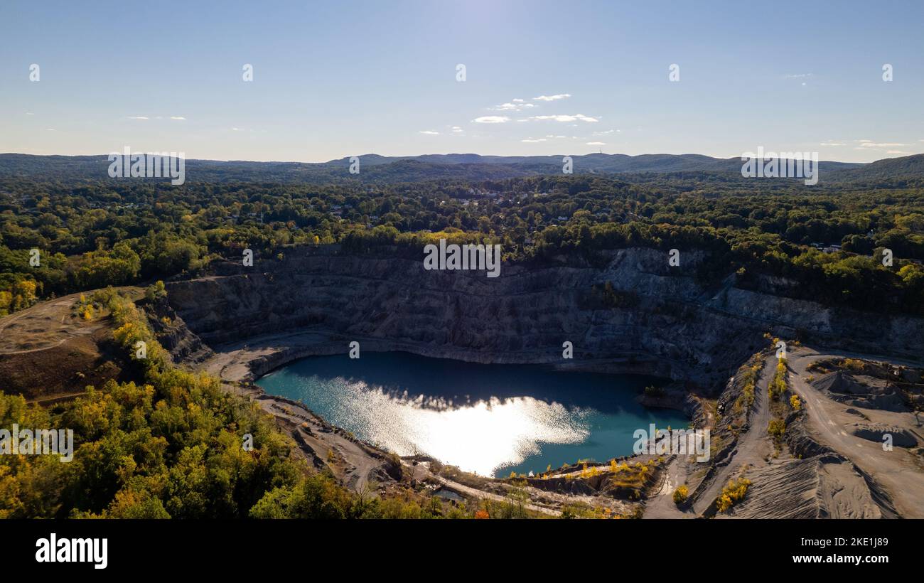 An aerial view over a rock quarry with turquoise colored water in ...
