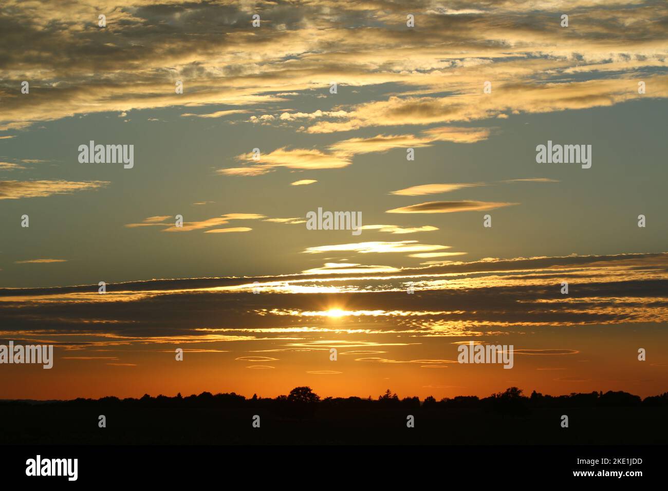 A glimpse of sunlight shinning through scattered clouds in a sunset sky ...