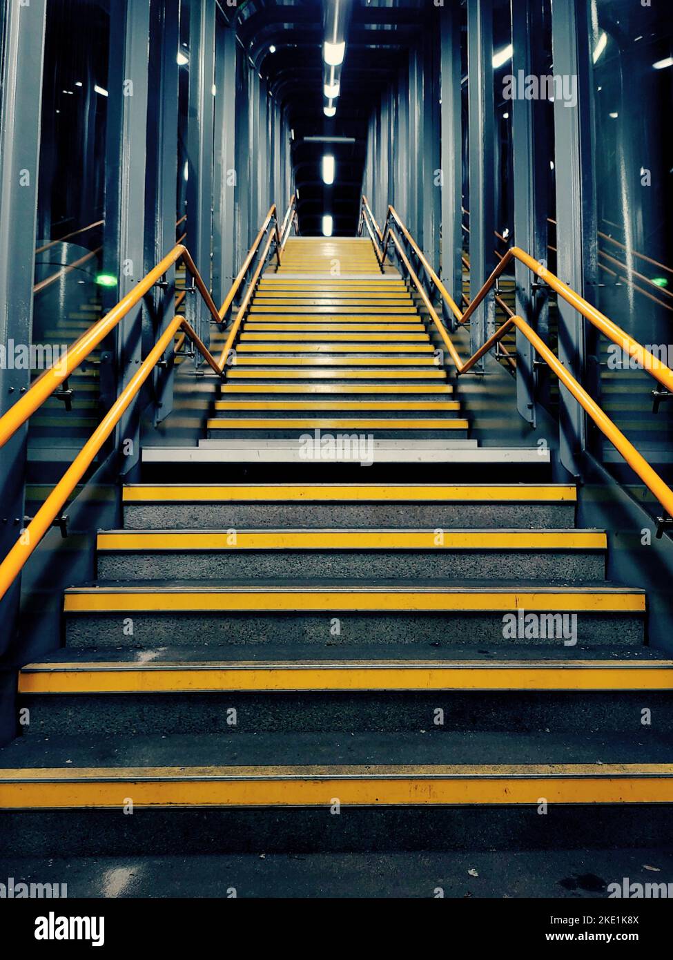 A vertical shot of a cascade of yellow stairs leading upward in a glass ...