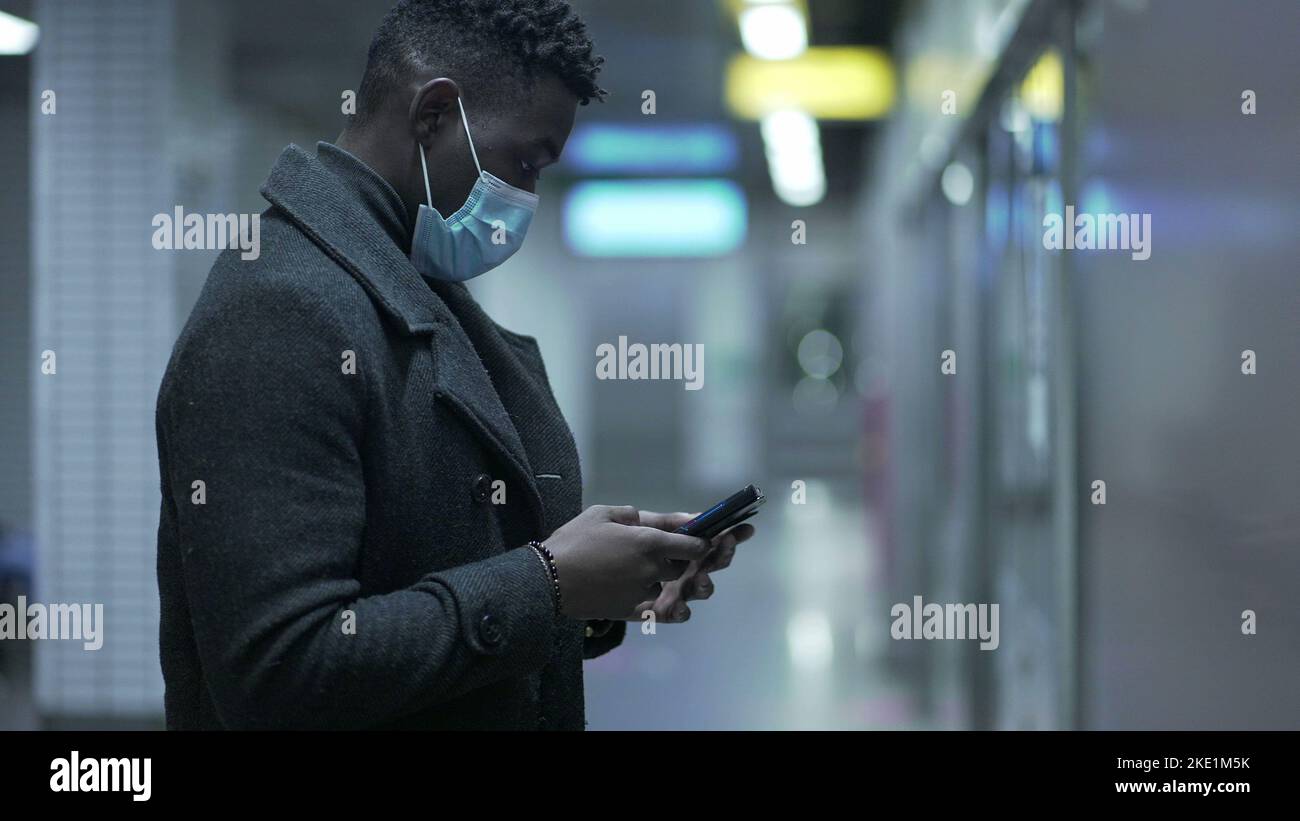 African man in subway metro wearing covid-19 face mask and looking at ...