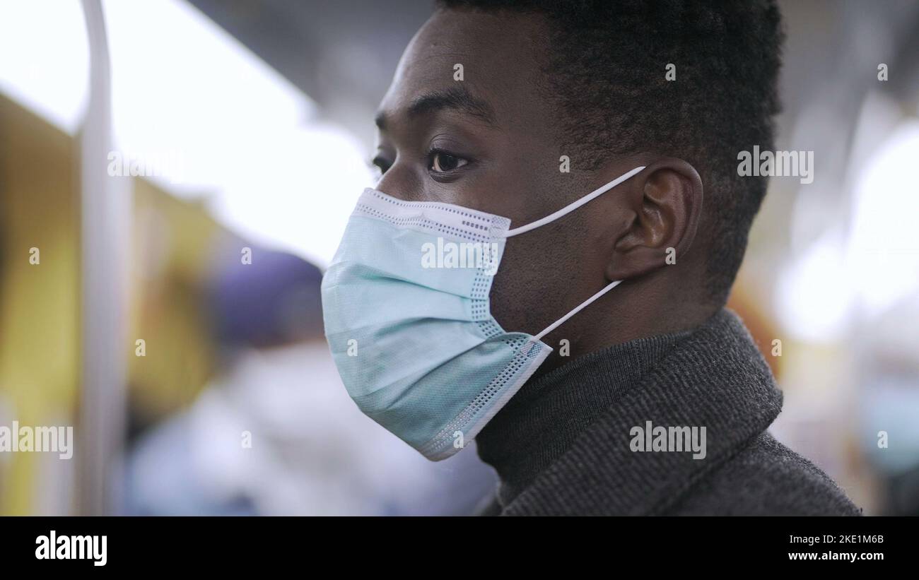 African man face close-up wearing covid-19 face mask inside public ...