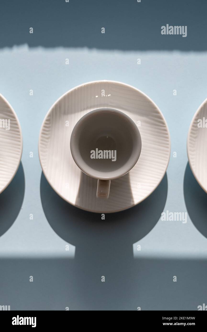 A top view of a white empty tea cup on a saucer with a blue background ...