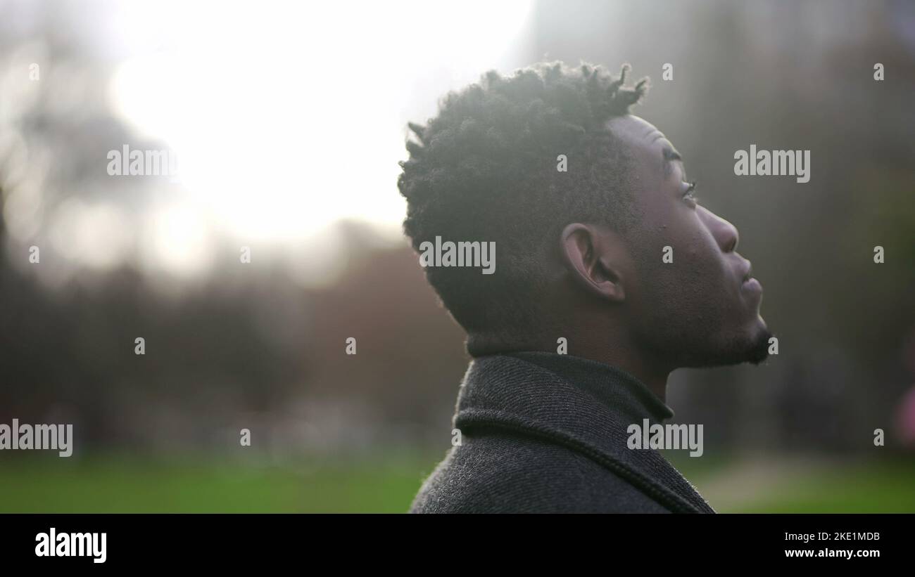 African young black man standing at park looking up in contemplation ...